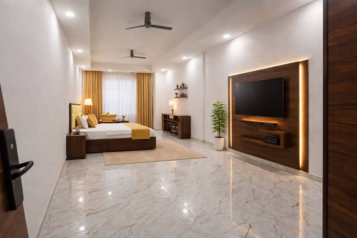 Quarto de hotel moderno com uma cama grande, televisão de tela plana, ventoinha no teto e piso de mármore.