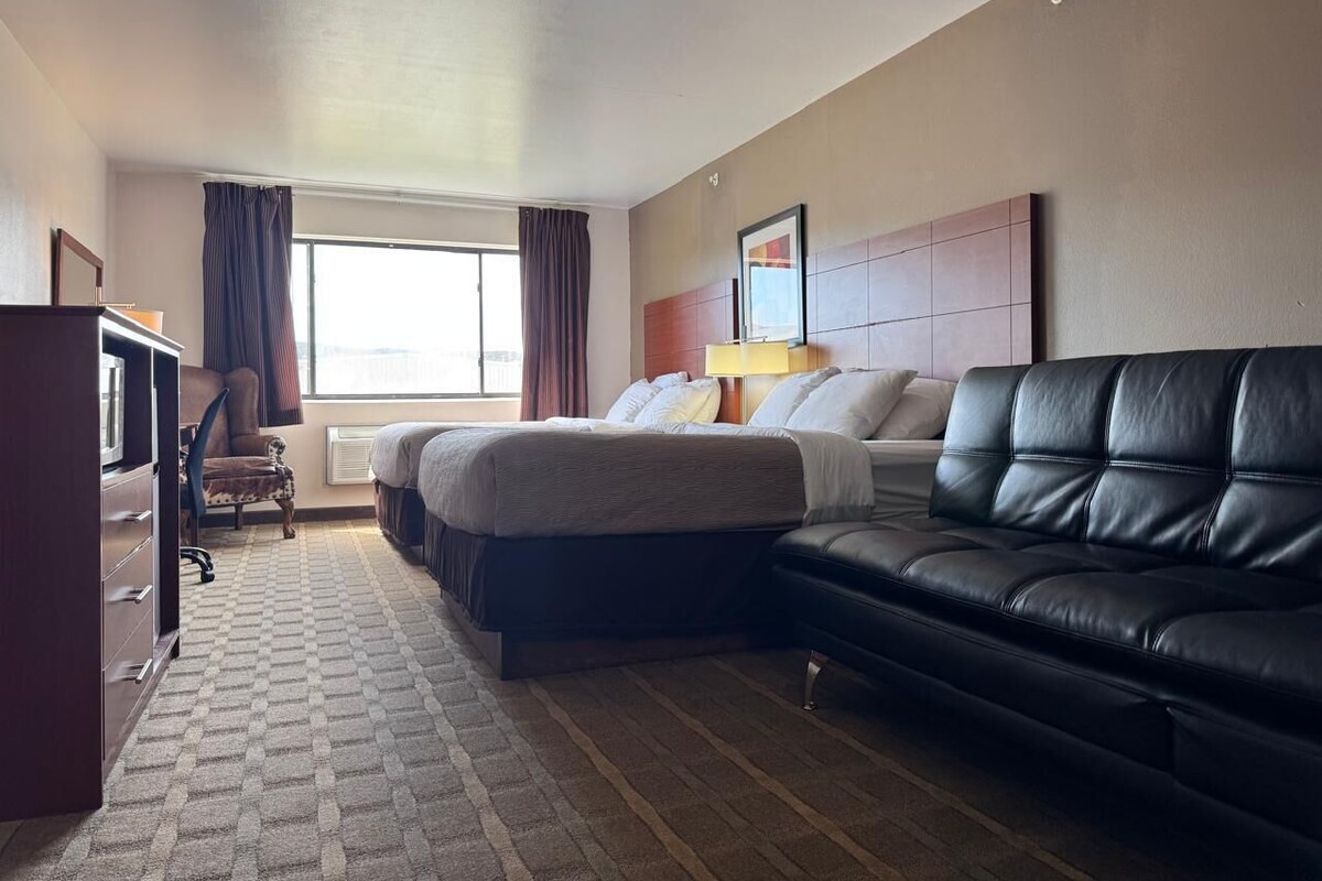 Quarto de hotel com cama, sofá, escrivaninha e cadeira.