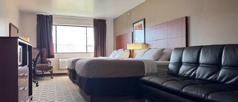 Quarto de hotel com cama, sofá, escrivaninha e cadeira.