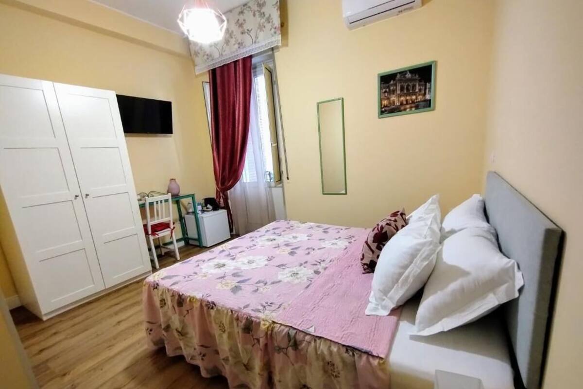 Quarto com cama, escrivaninha, cadeira, guarda-roupa e janela com cortinas.