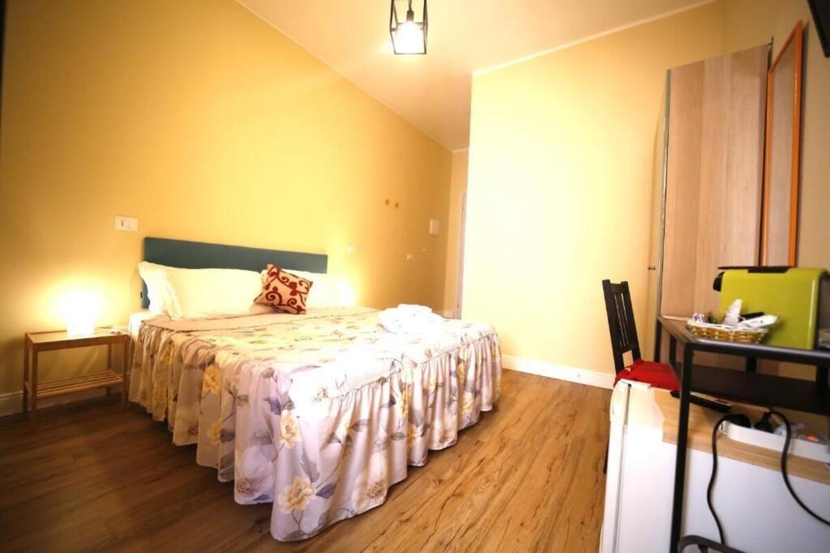 Quarto com cama, mesas de cabeceira, uma cadeira, escrivaninha e guarda-roupa.