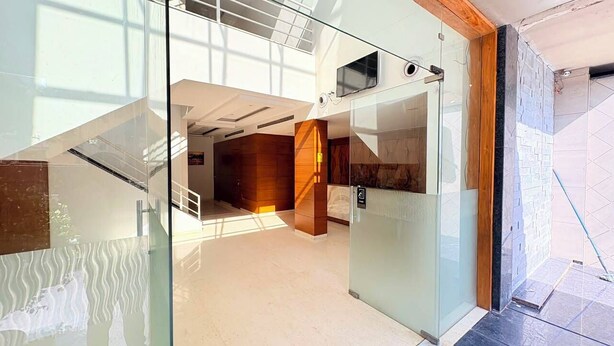 Interior moderno com divisórias de vidro, uma escada e vista para o exterior.