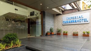 Exterior do Hotel Imperial Tamanna, com entrada moderna, portas de vidro e plantas em vasos.