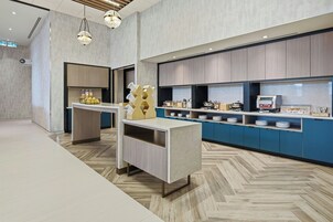 Cozinha moderna com ilha central, armários azuis e piso de madeira em padrão herringbone.