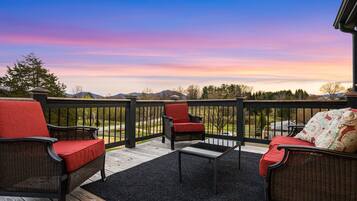 Um terraço com mobiliário de vime, uma pequena mesa e vista para a paisagem.