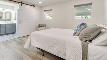 Um quarto com cama, porta deslizante, janela e ventoinha no teto.