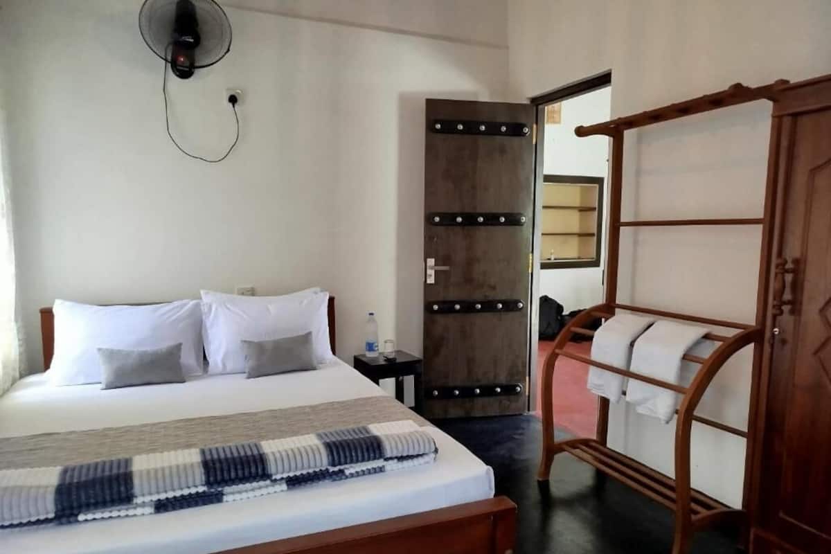 Quarto com cama, mesa de cabeceira e guarda-roupa.