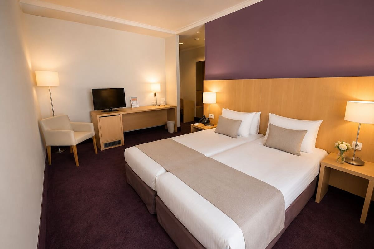 Quarto de hotel com uma cama grande, uma mesa, uma televisão e uma cadeira.