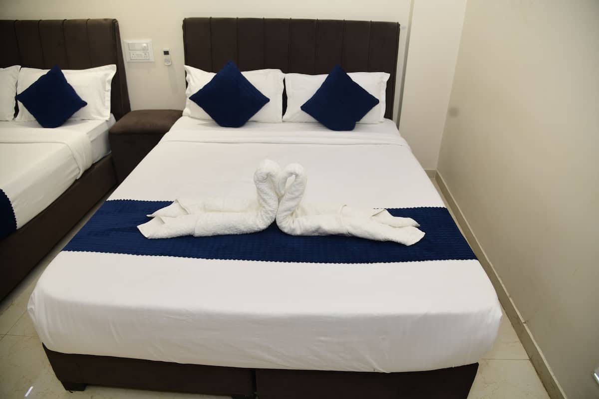 Quarto de hotel com duas camas, cada uma com cabeceira, roupa de cama branca e almofadas azuis.