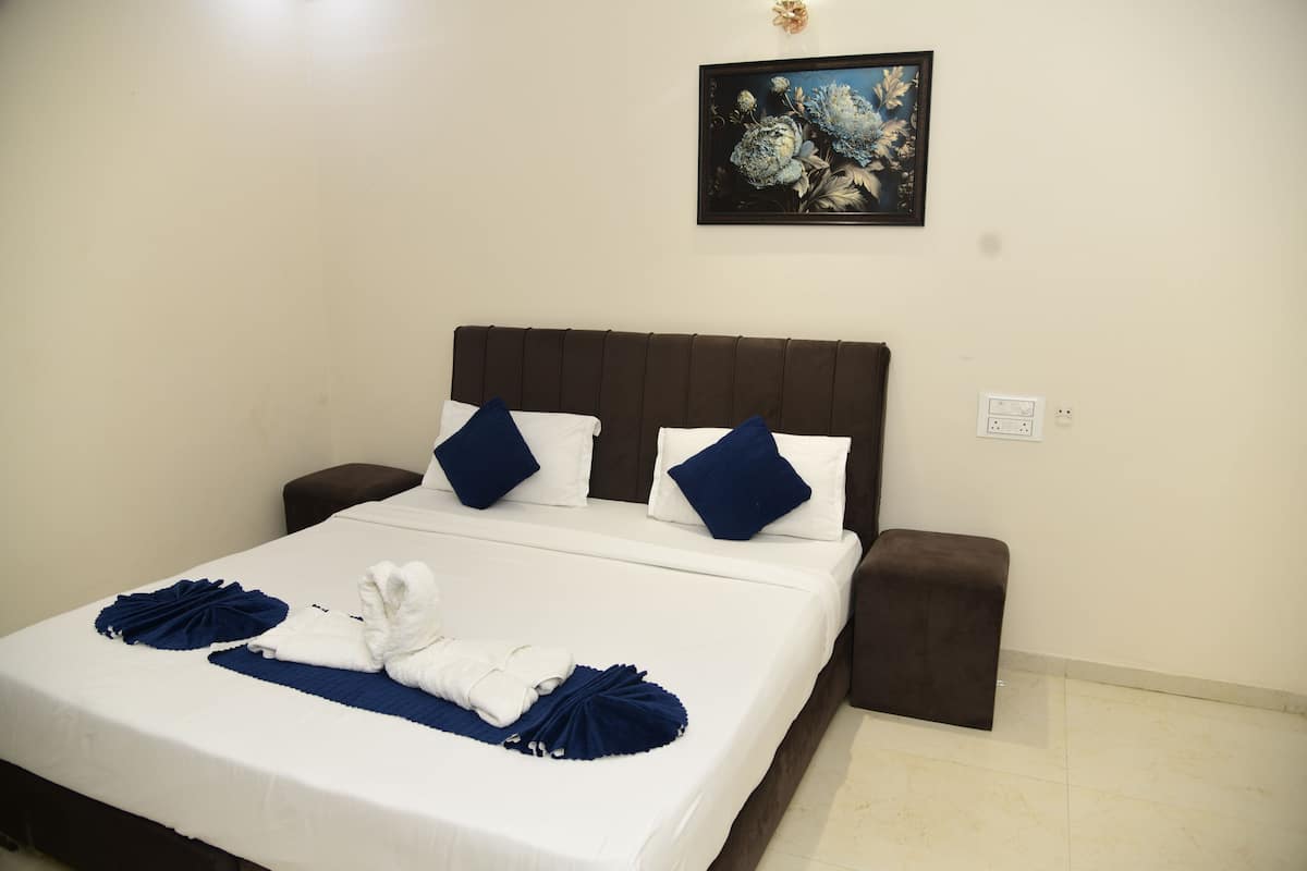Cama bem arrumada com almofadas azuis e brancas, um cobertor azul e uma toalha dobrada.