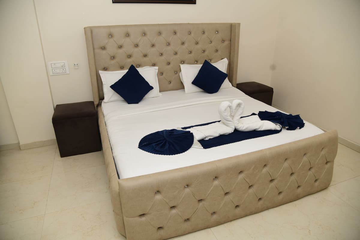 Uma cama bem arrumada com cabeceira estofada, dois travesseiros e uma toalha dobrada sobre a cama.