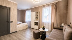Quarto de hotel moderno com uma cama, um sofá, uma mesinha e um guarda-roupa.