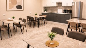 Uma cozinha moderna com armários escuros, uma geladeira de aço inoxidável e um espaço de jantar com mesa e cadeiras de mármore.
