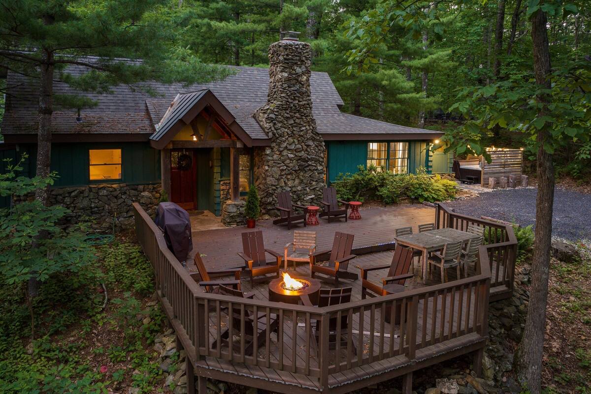 Uma cabana com chaminé de pedra, área de estar externa e um poço de fogo.