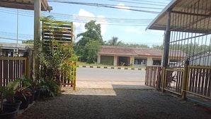 Uma entrada protegida por grades, com um caminho de cascalho que leva a um edifício com telhado de cerâmica.