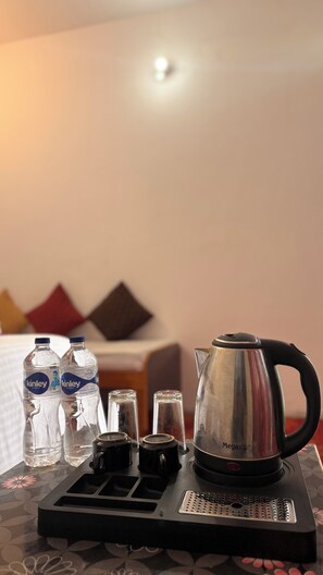Uma mesa com chaleira, garrafas de água e cafeteira em um quarto de hotel.