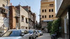 Rua estreita com carros estacionados e edifícios.