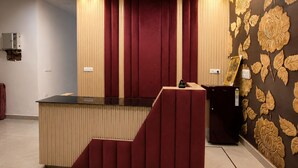 Uma mesa de recepção com design em painel de madeira, uma parede de destaque vermelha e um painel floral decorativo.