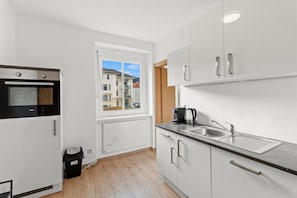 Uma cozinha moderna com forno embutido, pia e janela com vista para edifícios.