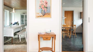 Quarto com área de jantar, mesa com um vaso de flores e um quadro na parede.