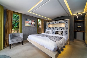Quarto moderno com cama, uma cadeira, escrivaninha e um pequeno frigorífico.