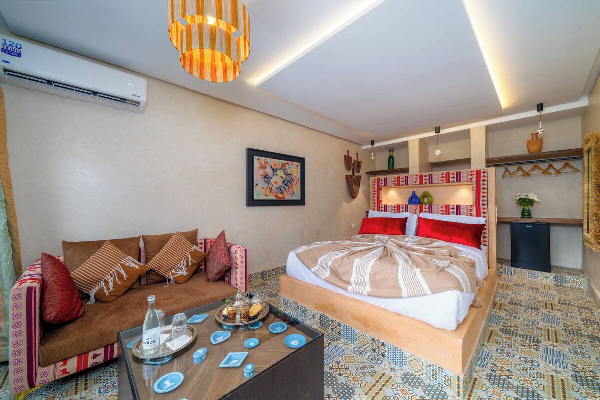 Quarto de hotel com cama, sofá e uma pequena mesa com uma bandeja de objetos.