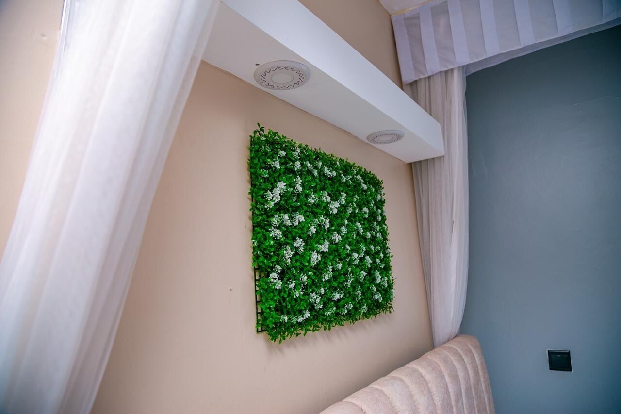 Paredes com um painel floral verde, teto branco e um interruptor de luz.