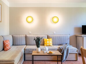 Uma sala de estar moderna com um sofá seccional, uma mesa de centro e duas luminárias fixadas na parede.