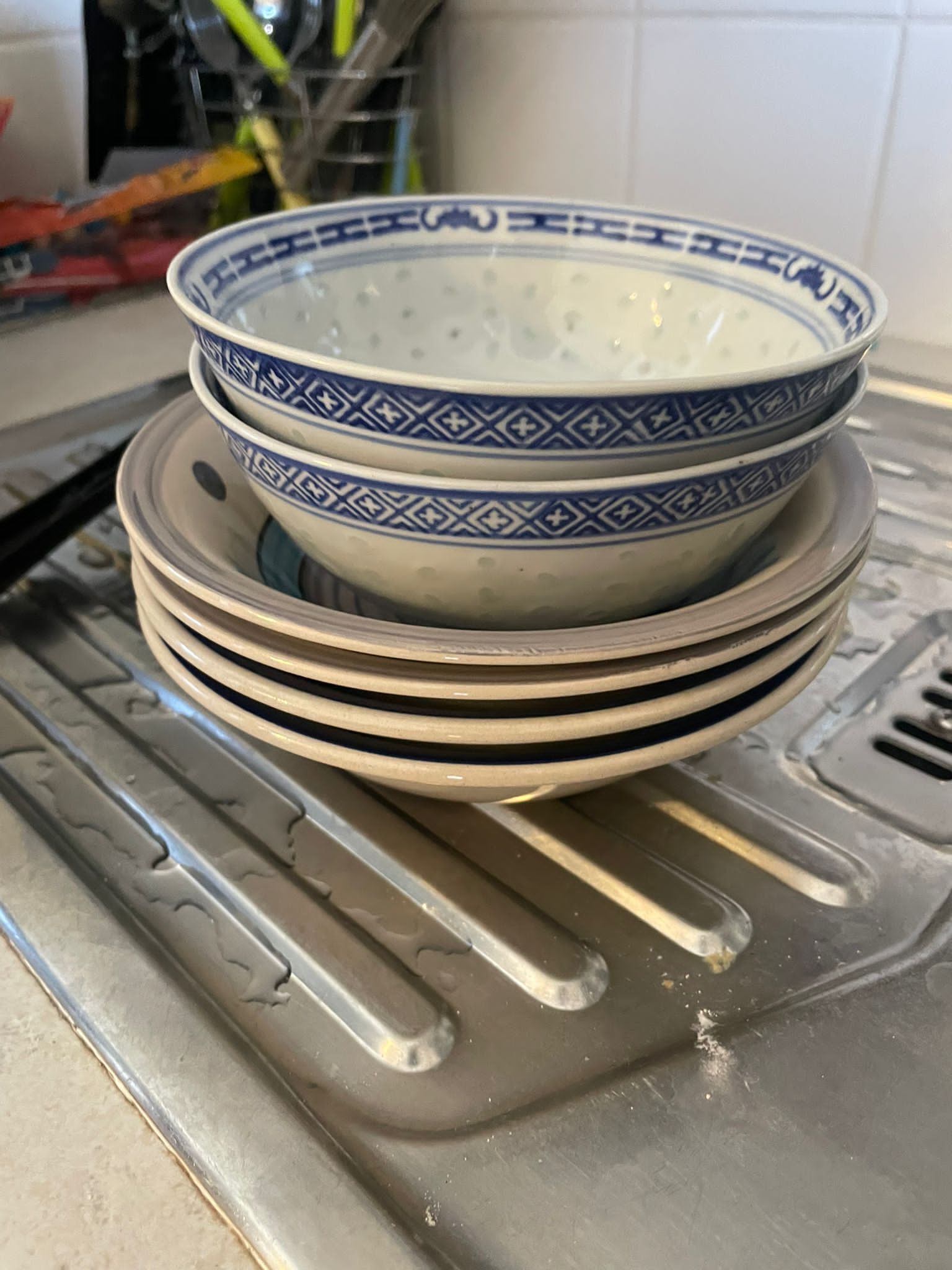 Uma pilha de tigelas brancas com padrões azuis sobre uma superfície metálica.