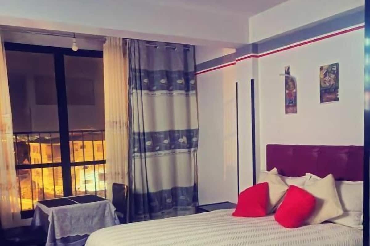 Quarto de hotel com cama, mesa e cadeira.