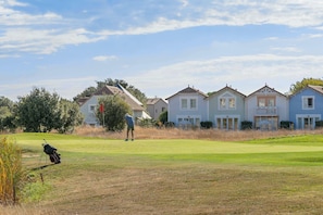 Um campo de golfe com casas ao fundo.