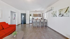 Uma sala de estar moderna com um sofá vermelho, uma cozinha com banquetas e uma área de refeições.
