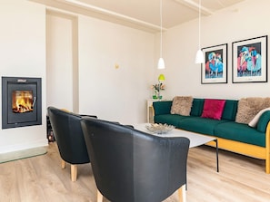 Uma sala de estar moderna com lareira, um sofá verde, cadeiras pretas e obras de arte na parede.