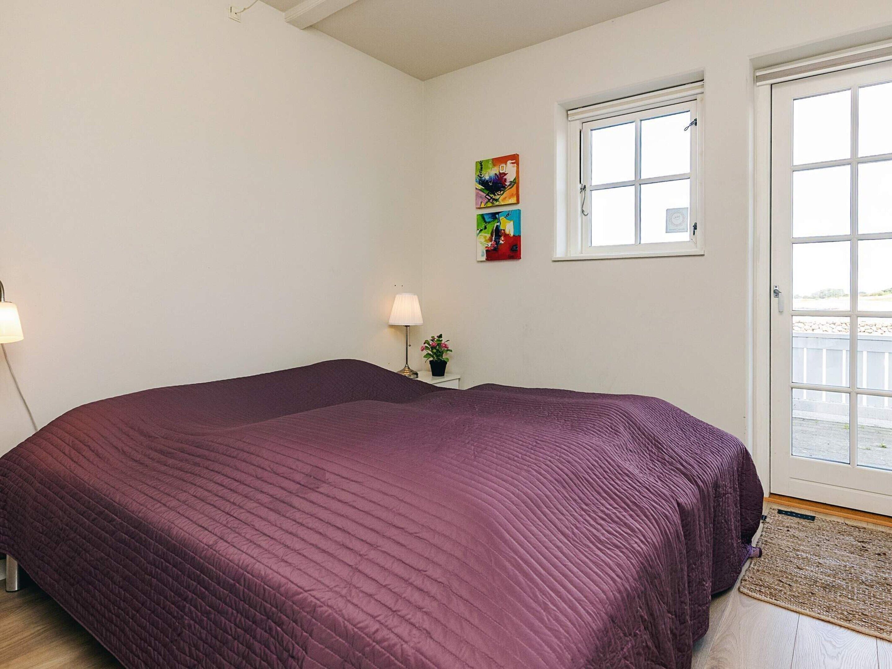 Quarto com uma cama grande, uma janela e uma porta.
