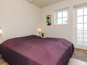 Quarto com uma cama grande, uma janela e uma porta.