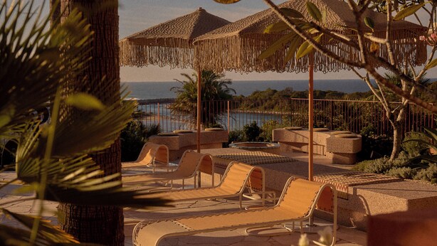 Área de piscina do resort, com espreguiçadeiras, guarda-sóis e vista para o mar.