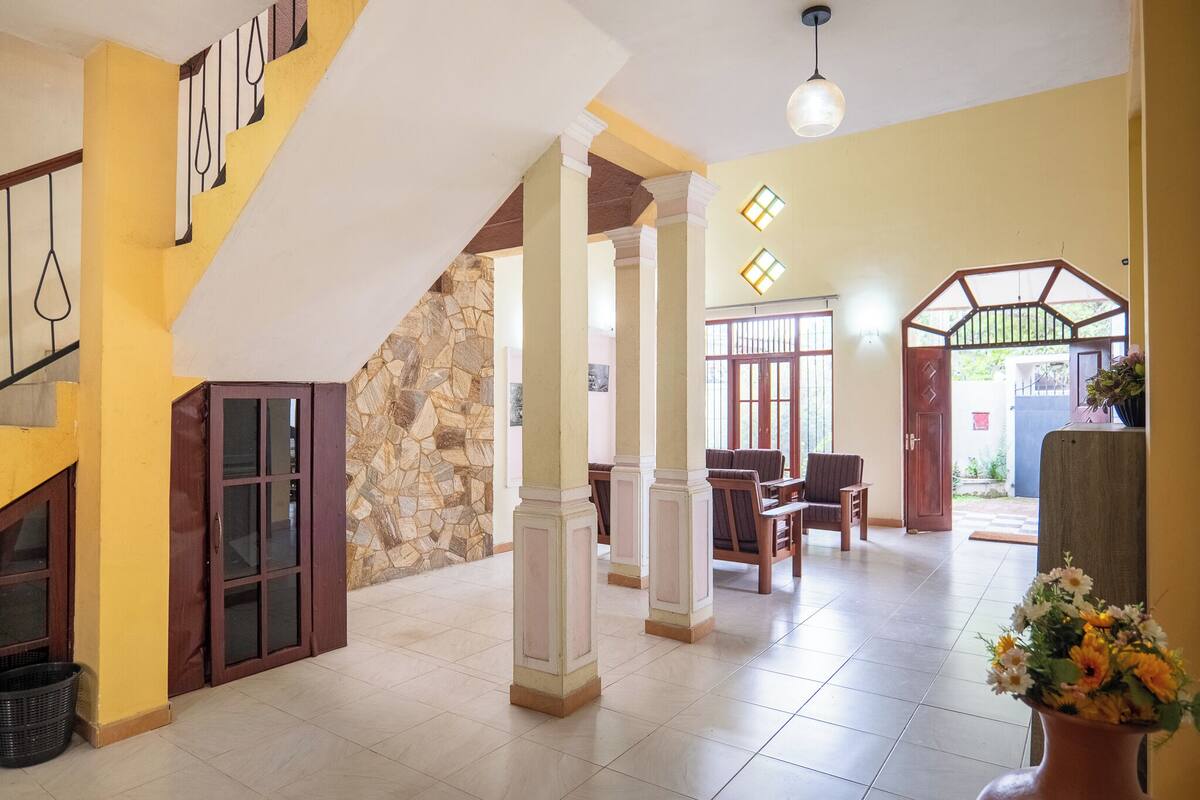 Um hall amplo com escada, parede de pedra e vista para o exterior.