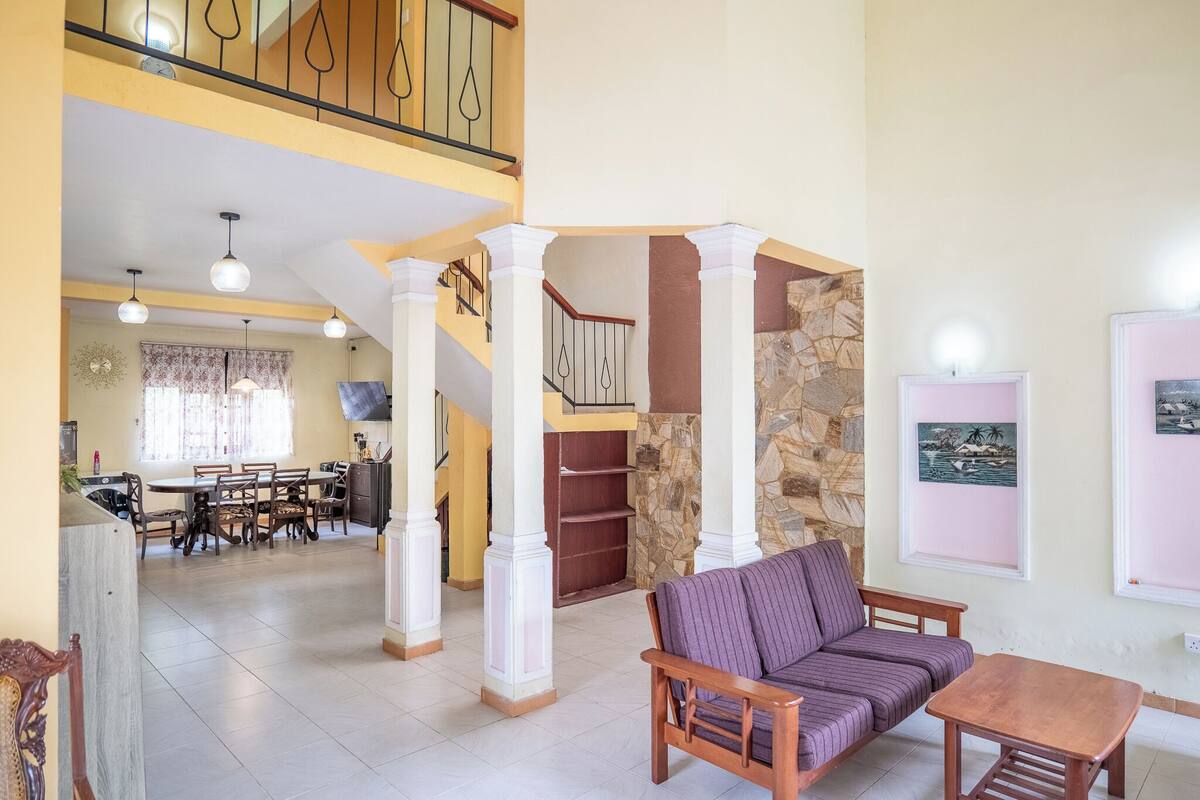 Uma sala ampla com mesa de jantar, sofá e escada.