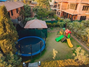 Um bairro residencial com um trampolim, um escorrega e um quintal cercado.