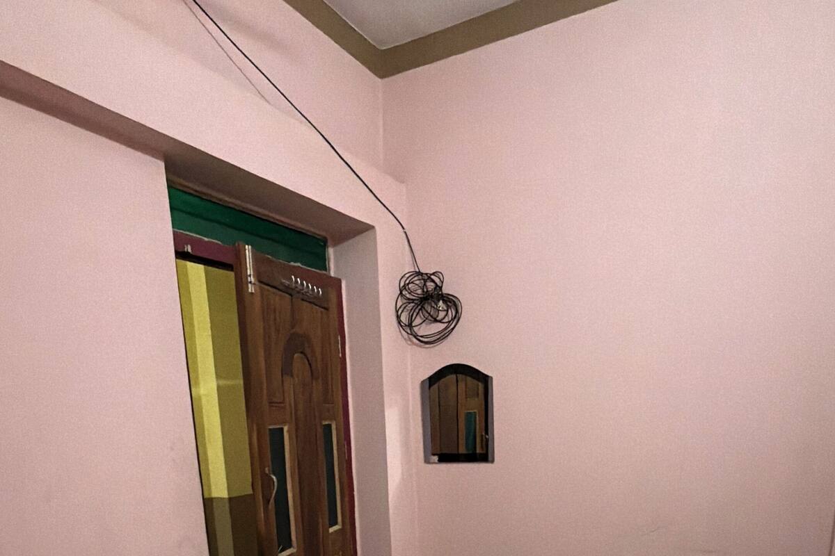 Quarto com uma cama, uma porta de madeira e uma janela pequena.