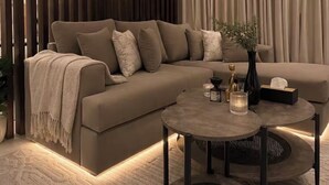 Uma sala de estar moderna com um sofá modular, uma mesa de centro redonda e uma parede com ripas verticais.
