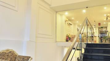 Um interior em vários níveis, com escada, lustre e sofá.