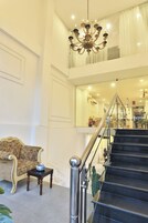 Um interior em vários níveis, com escada, lustre e sofá.