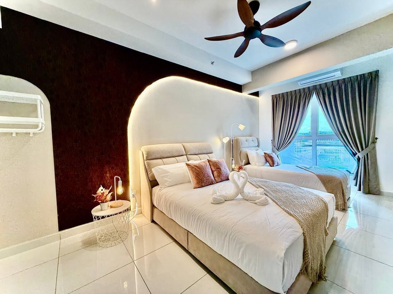 Quarto moderno com uma cama grande, ventilador de teto e vista para a cidade.