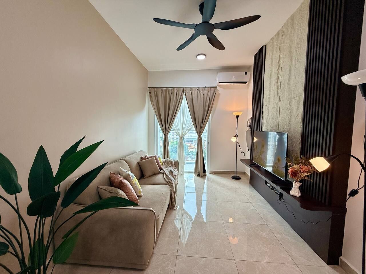 Sala de estar moderna com sofá, televisão e plantas decorativas.