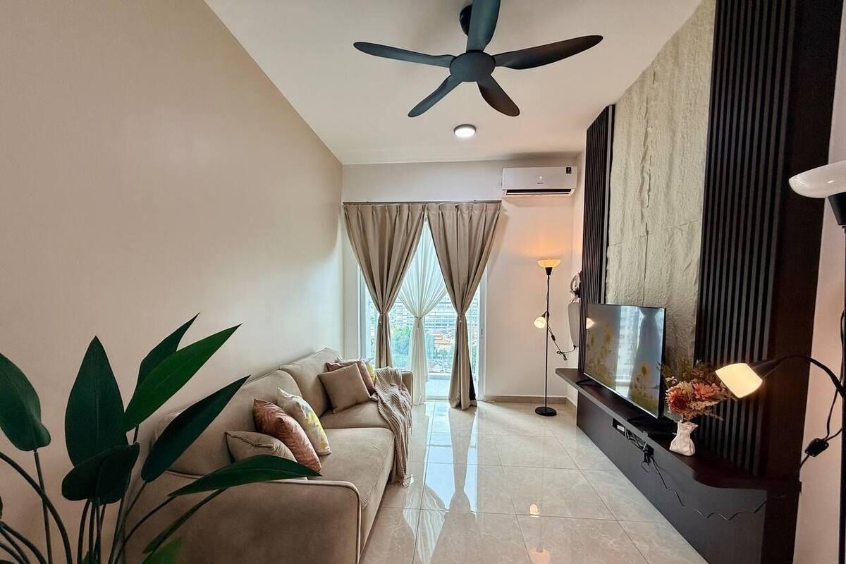 Sala de estar moderna com sofá, televisão e plantas decorativas.
