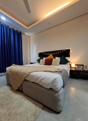 Um quarto moderno com cama, mesas de cabeceira e um criado-mudo.