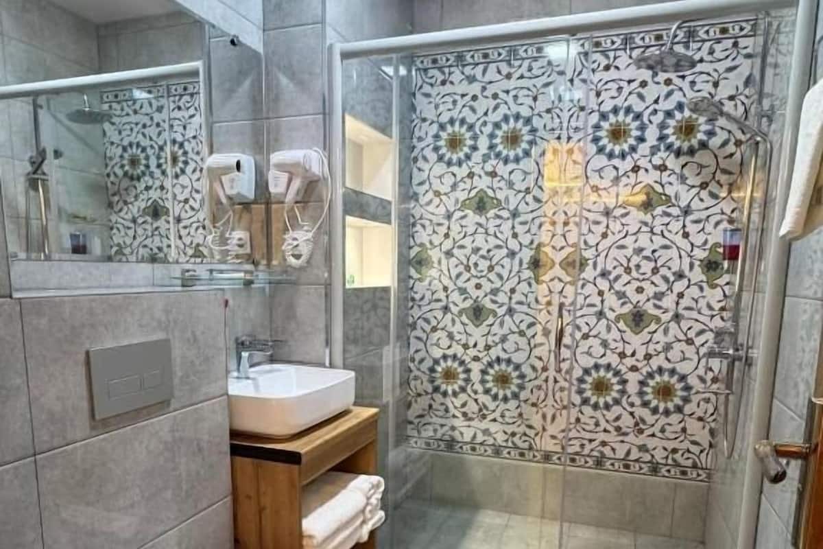 Casa de banho com sanita, lavatório e chuveiro com porta de vidro.