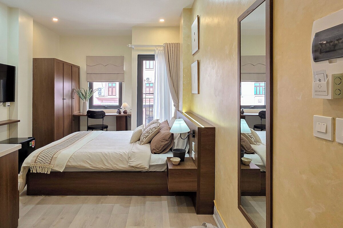 Quarto com cama, mesa de cabeceira, abajur e espelho.