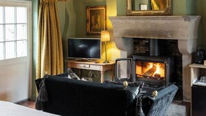 Um quarto aconchegante com lareira, um candelabro, uma cama e uma televisão.